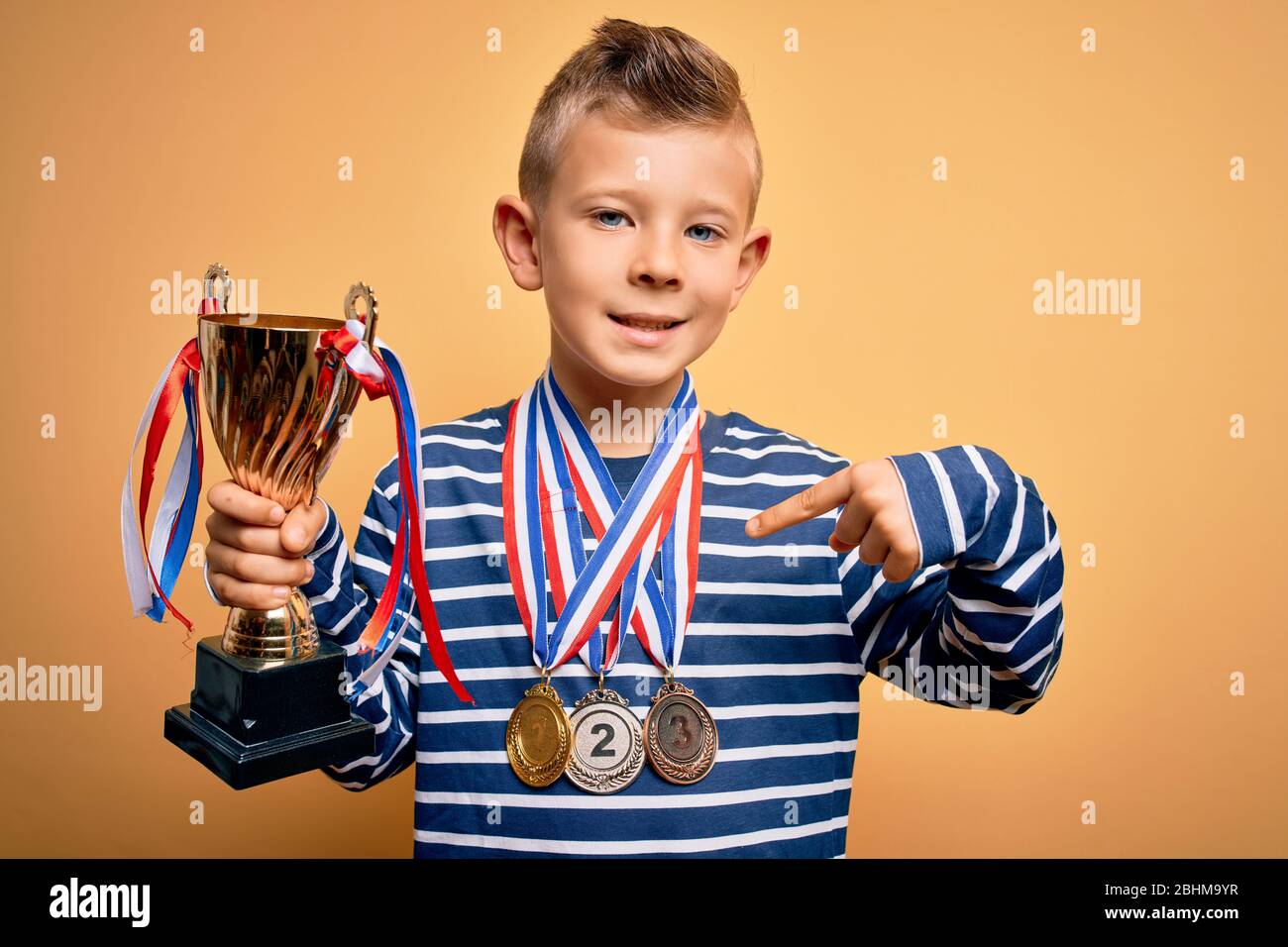 Young little caucasian kid wearing winner medals and victory award ...