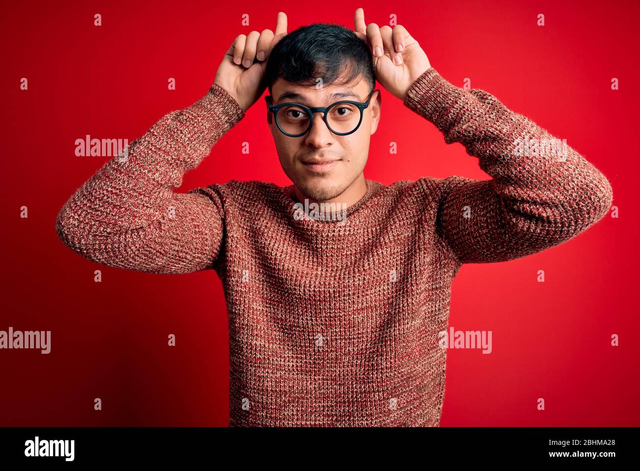 Young handsome hispanic man wearing nerd glasses over red background ...