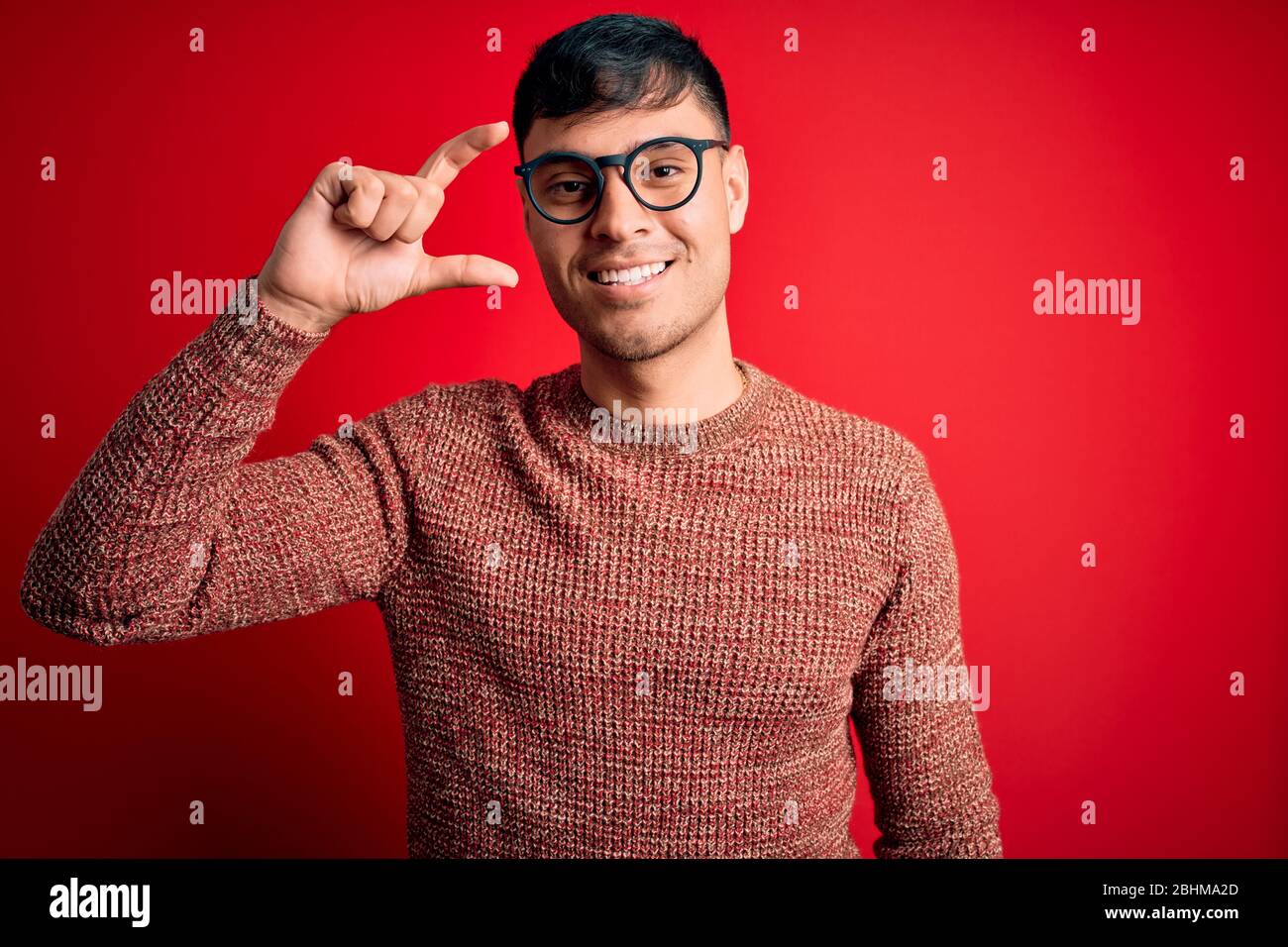 Young handsome hispanic man wearing nerd glasses over red background ...