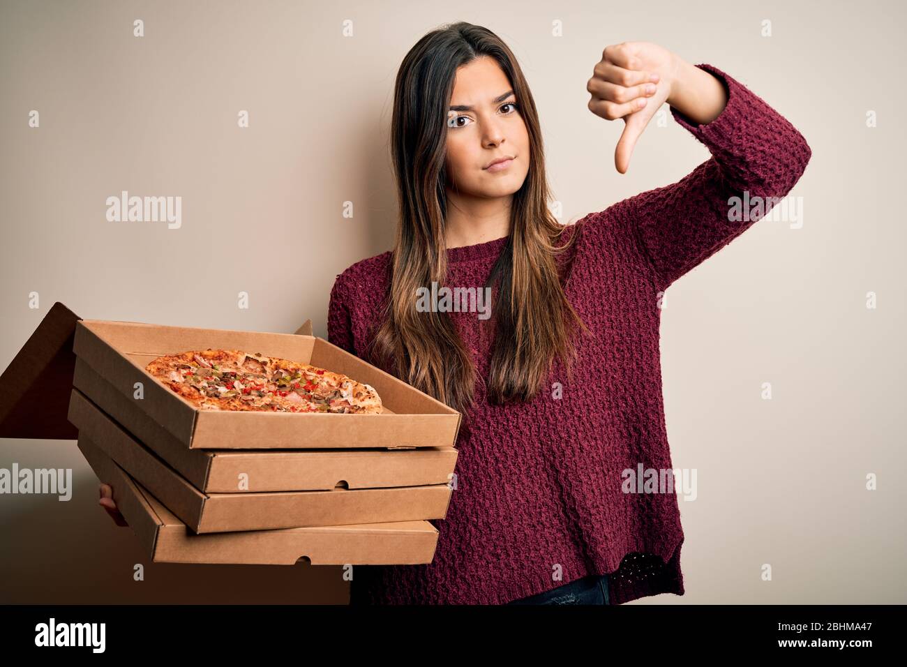 Young beautiful girl holding delivery boxes with Italian pizza standing ...