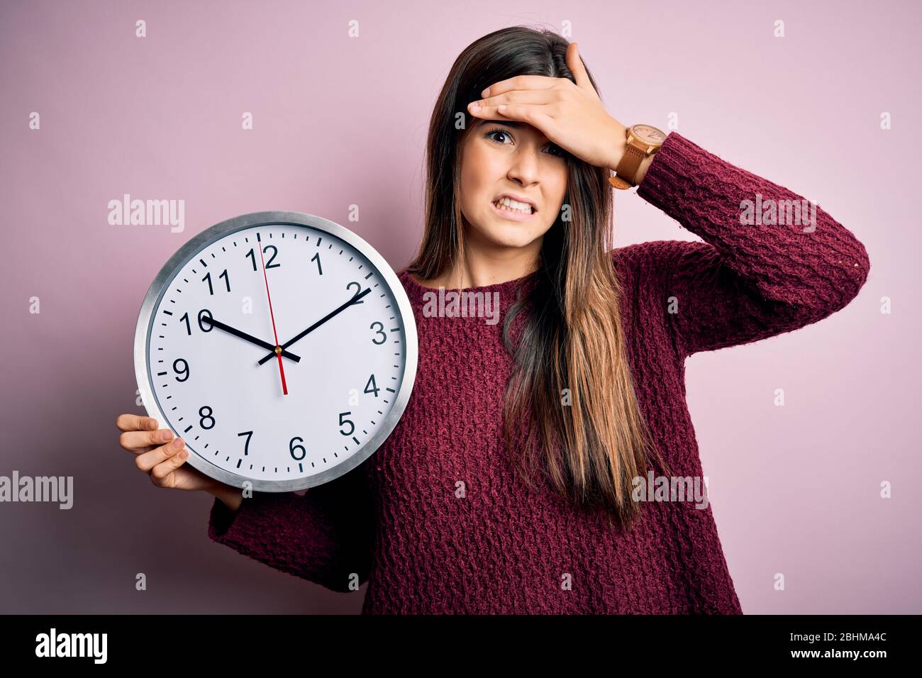 Young beautiful girl doing countdown holding big clock over isolated ...