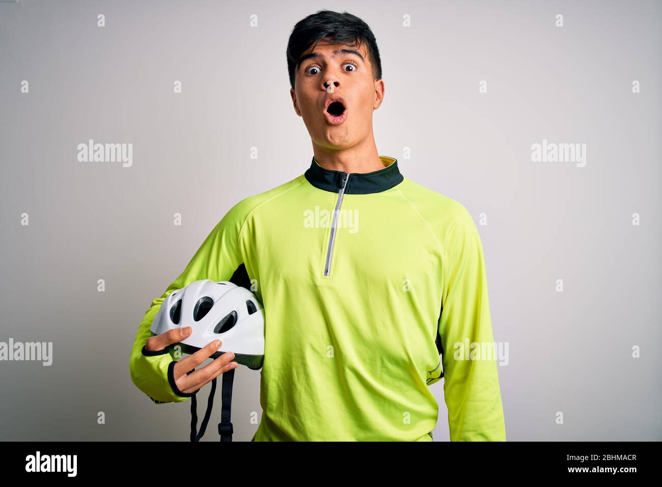 Young handsome cyclist man holding security bike helmet over isolated ...