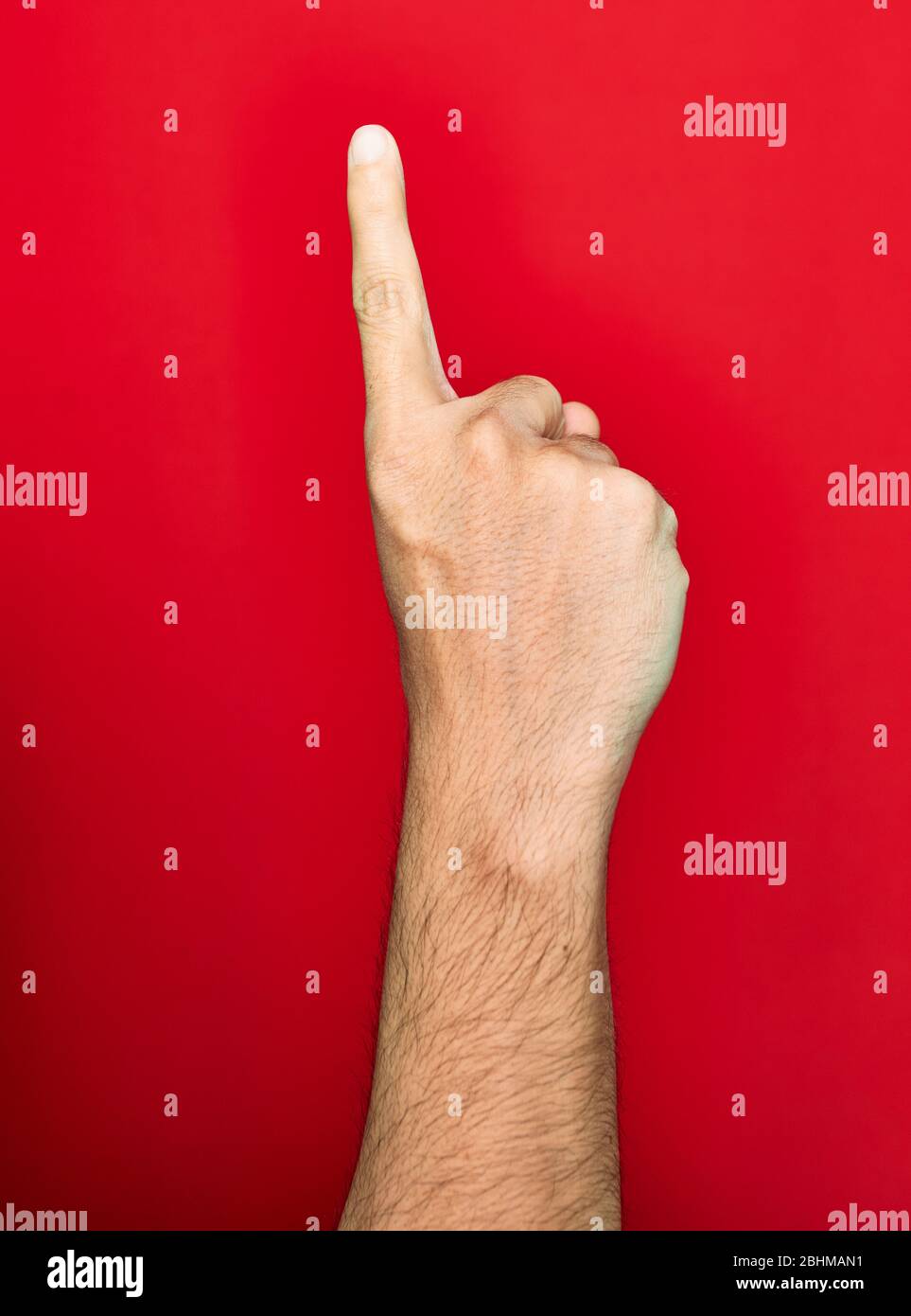 Beautiful hand of man raised up showing one finger over isolated red ...
