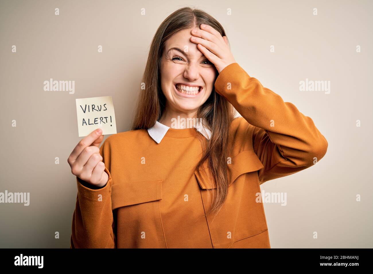 Young beautiful redhead woman holding reminder paper with virus alert ...