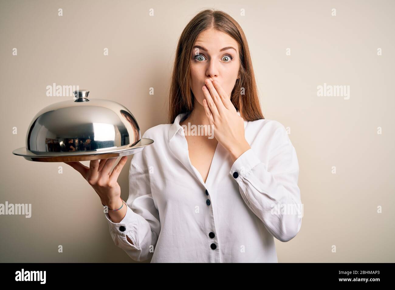 Young beautiful redhead woman holding waitress tray over isolated white ...