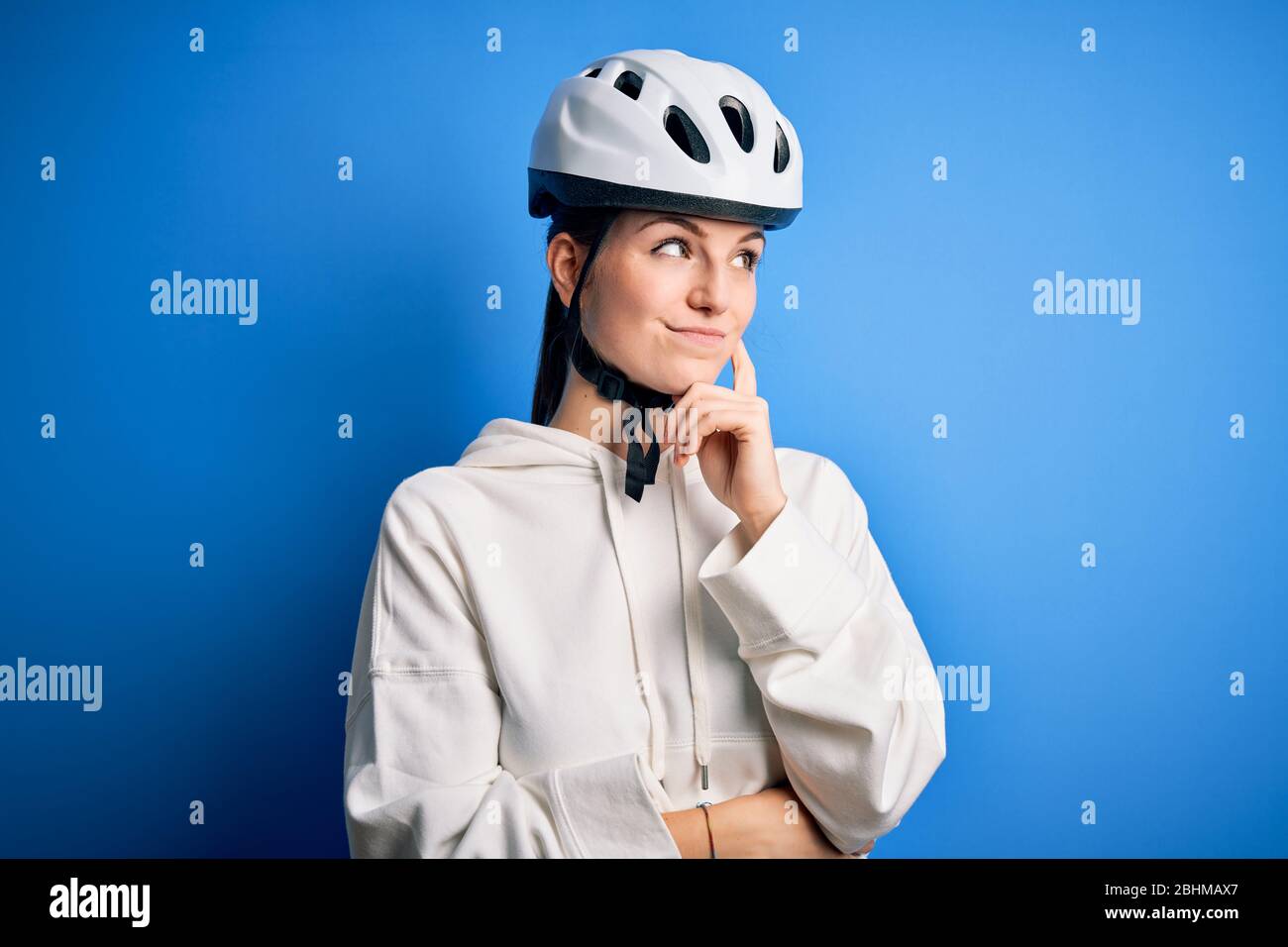 Young beautiful redhead cyclist woman wearing bike helmet over isolated ...