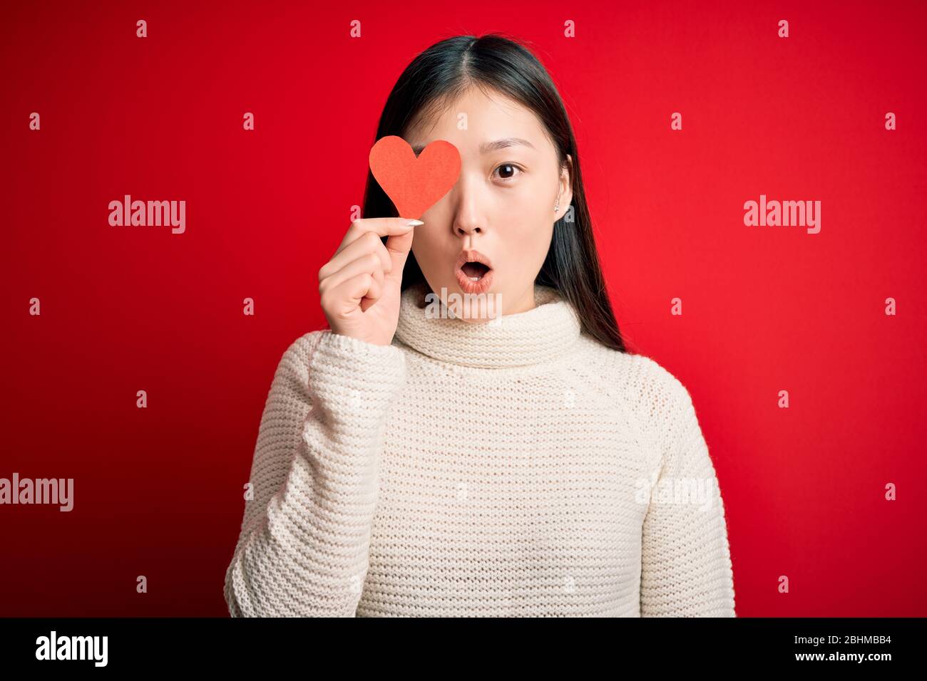 Young asian woman holding romantic red heart paper shape over red ...