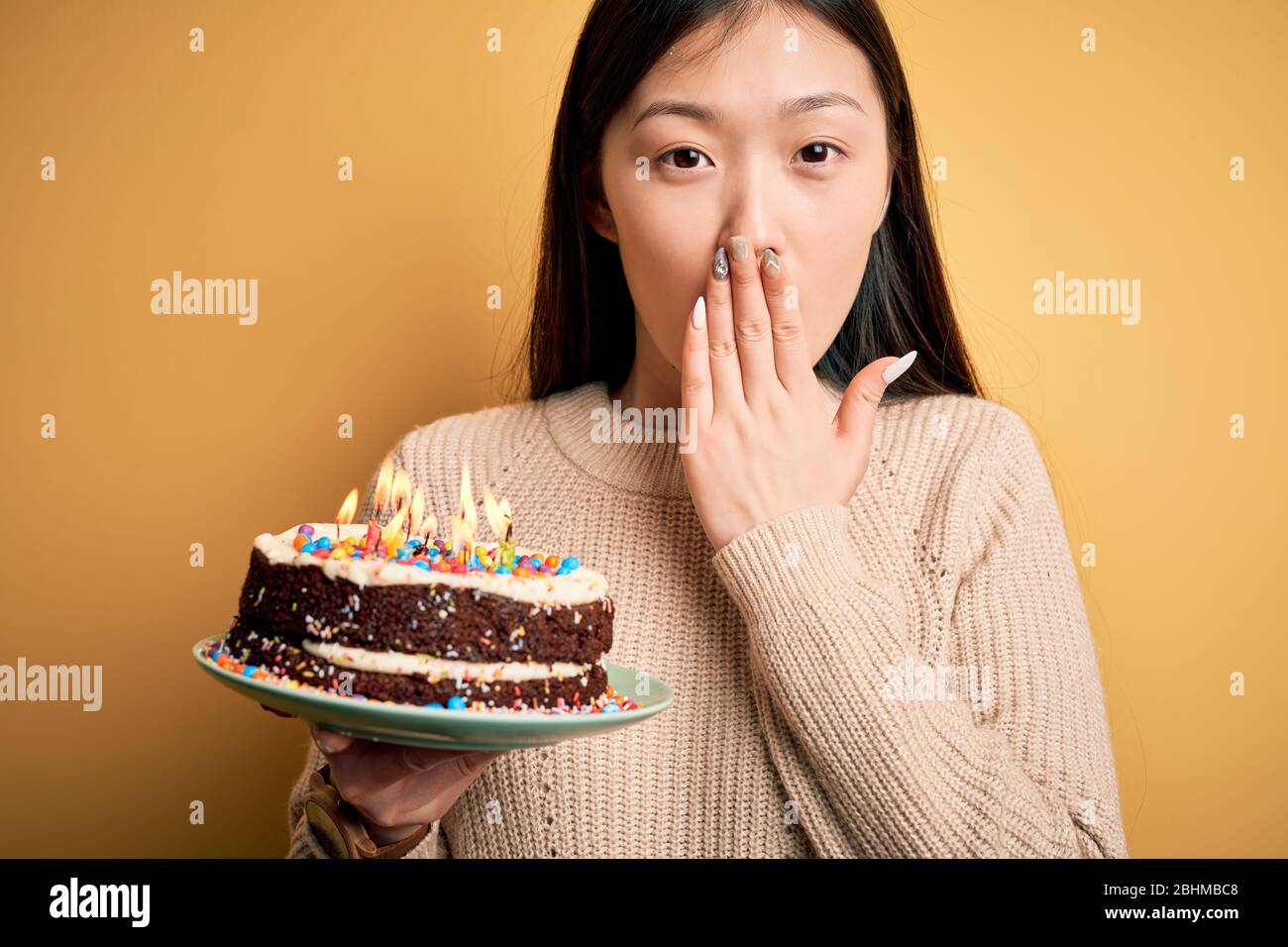 Young asian woman holding birthday cake with candles burning over ...