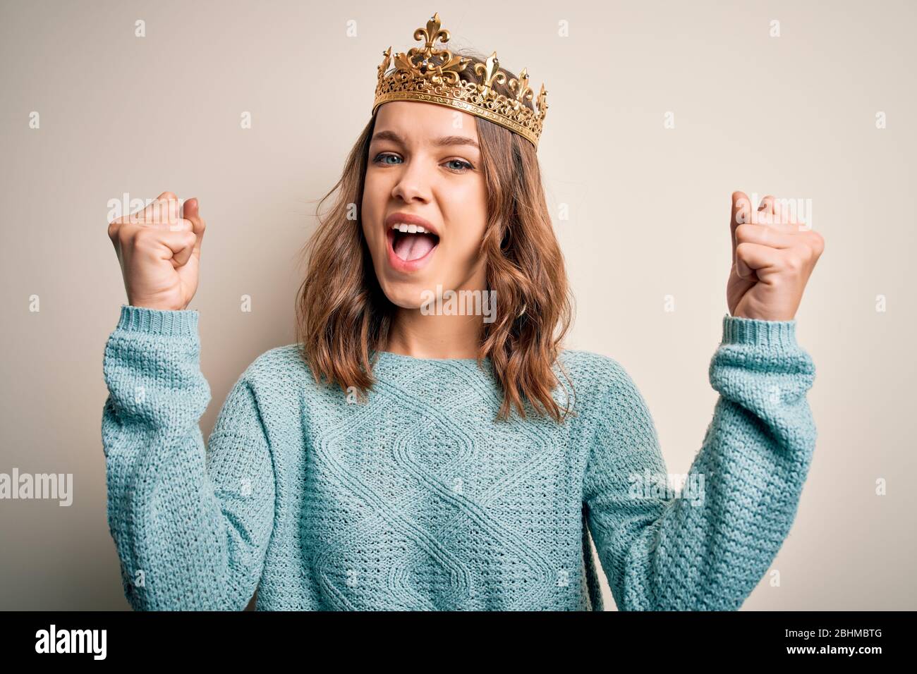 Young blonde girl wearing queen golden crown over isolated background ...