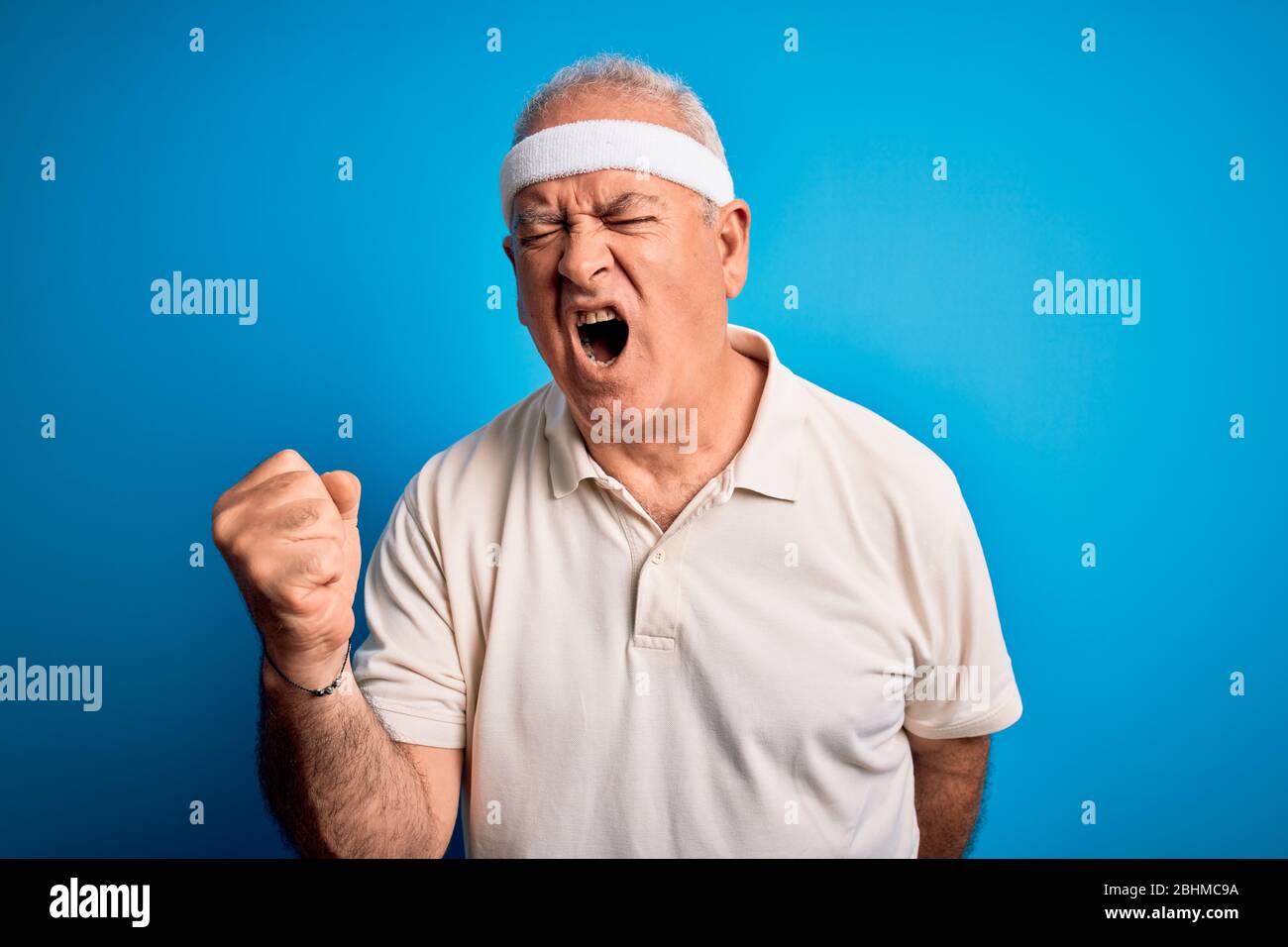 Middle age hoary sportsman doing sport wearing sportswear over isolated ...