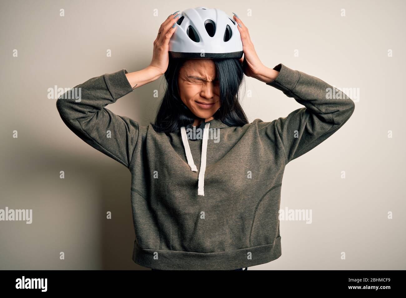 Young beautiful chinese woman wearing bike helmet over isolated white ...