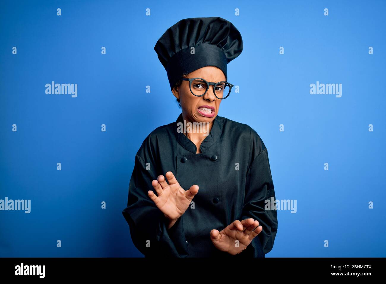 Young african american chef woman wearing cooker uniform and hat over ...