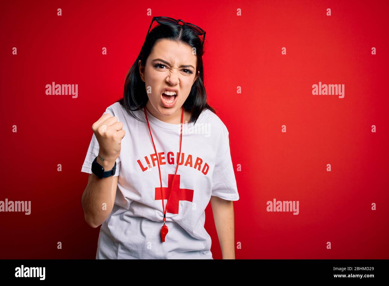 Young lifeguard woman wearing secury guard equipent over red background ...