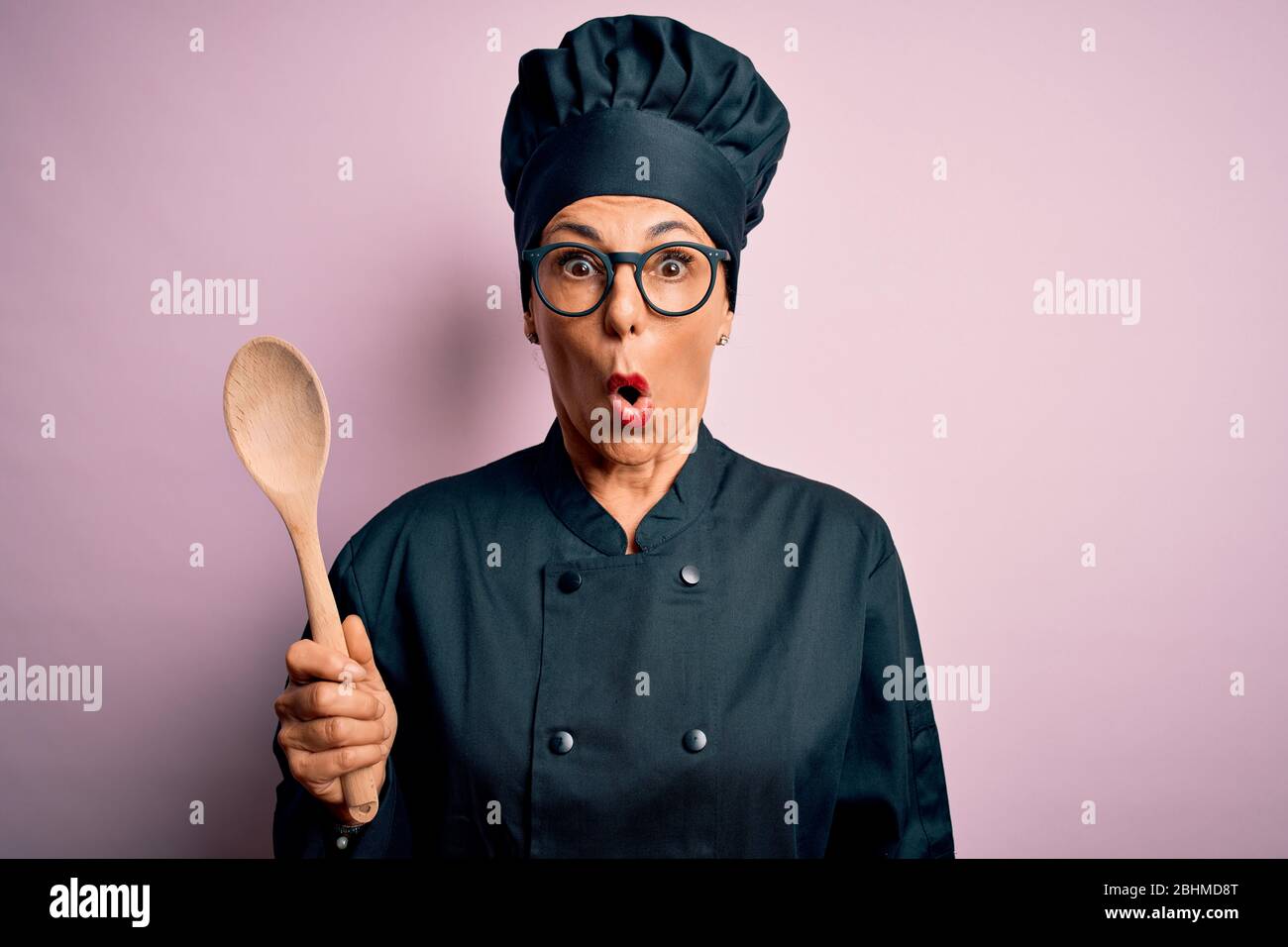 Middle age brunette chef woman wearing cooker uniform and hat holding ...