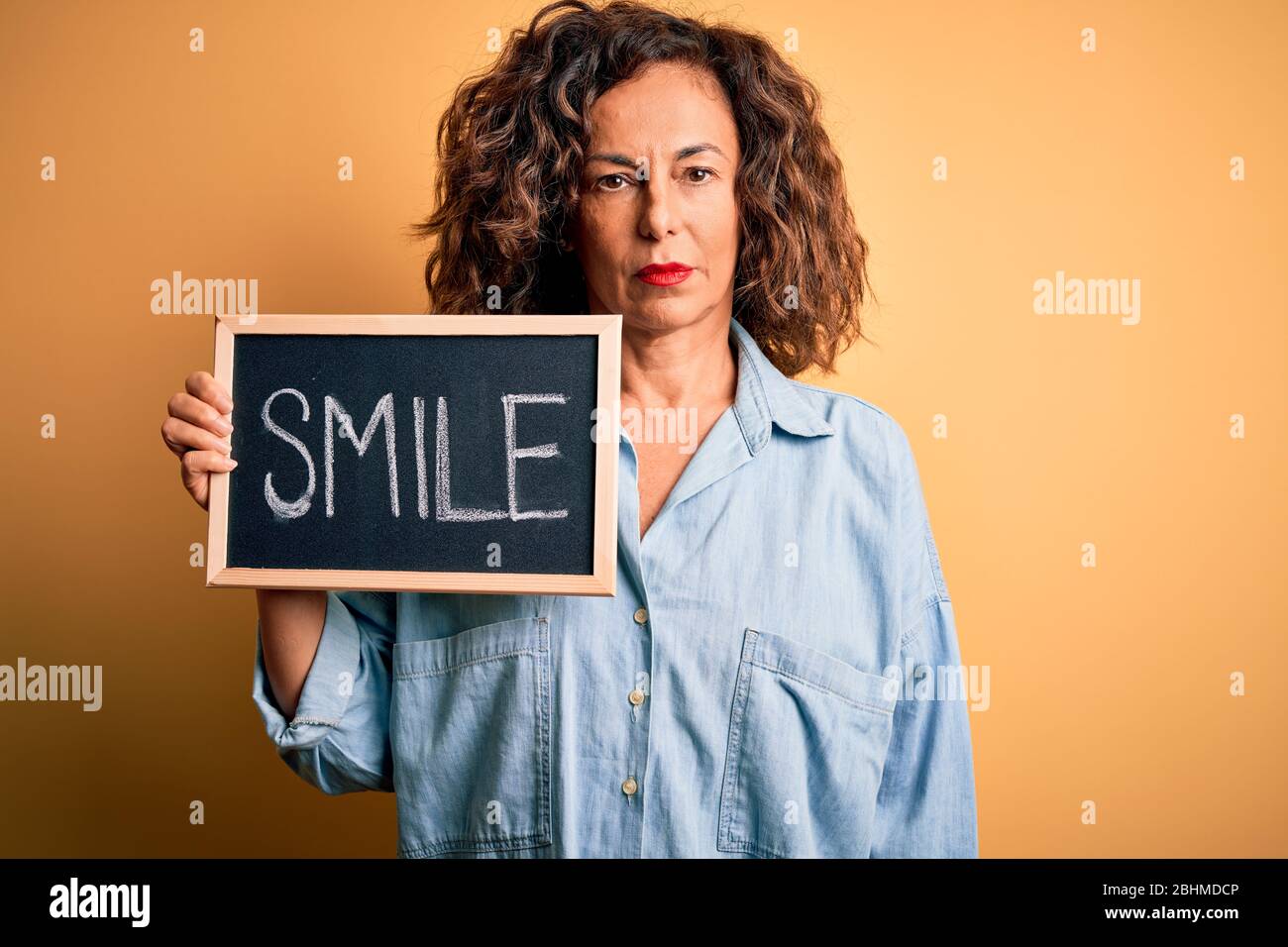 Middle age woman holding blackboard with smile message over isolated ...