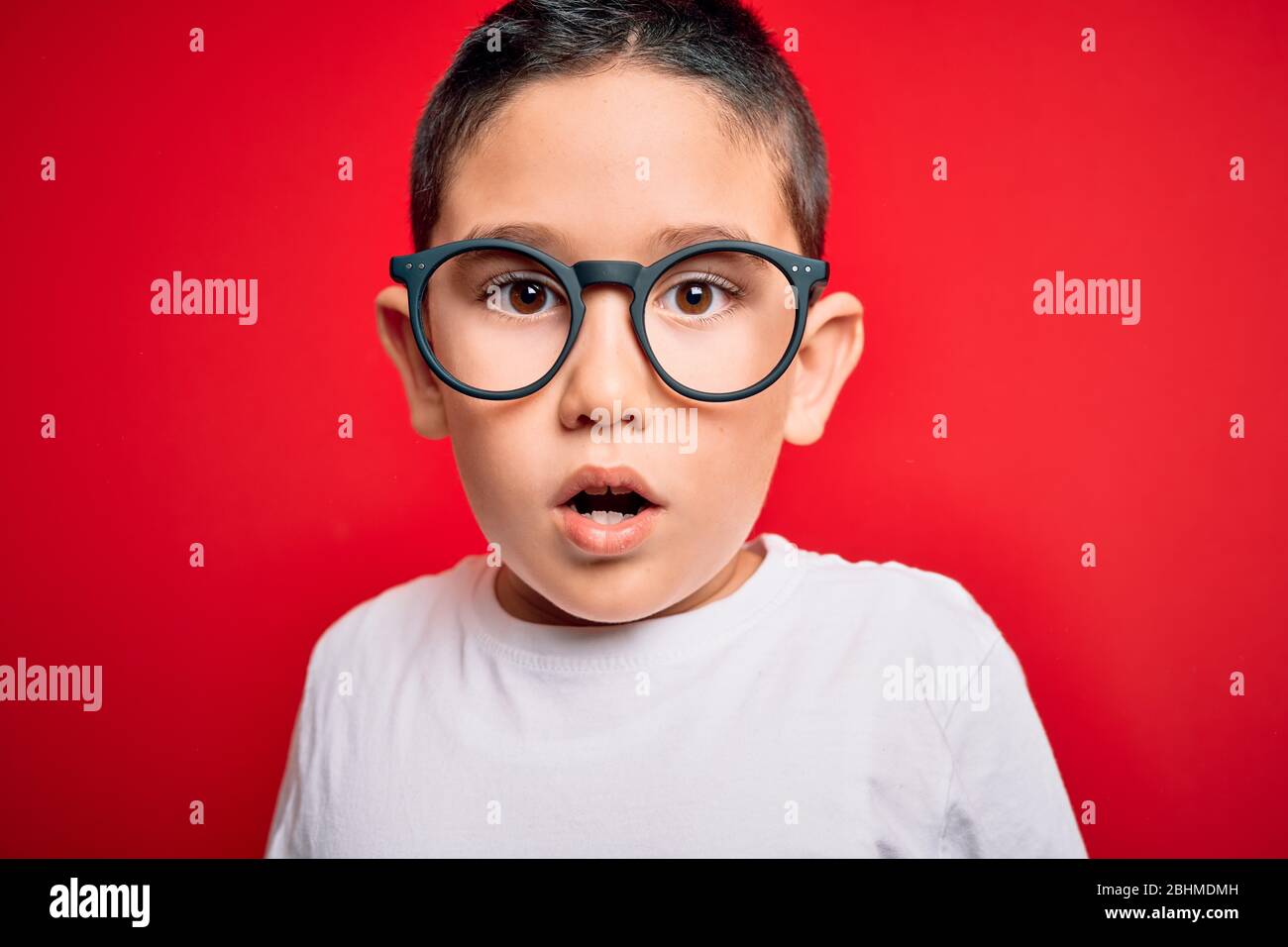 Young little smart boy kid wearing nerd glasses over red isolated ...