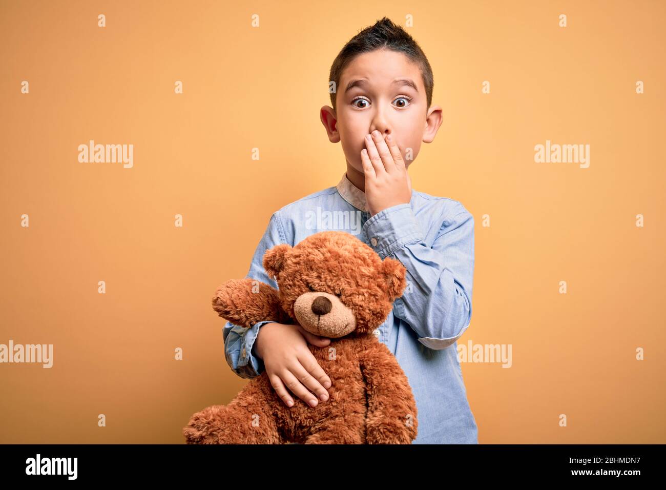 Young little boy kid hugging teddy bear stuffed animal over yellow ...