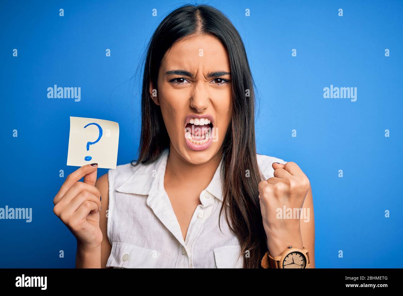 Young beautiful brunette woman holding paper with question mark symbol ...