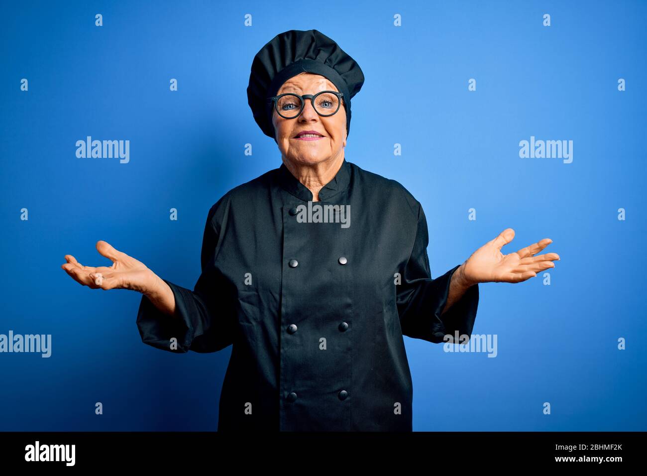 Senior beautiful grey-haired chef woman wearing cooker uniform and hat ...