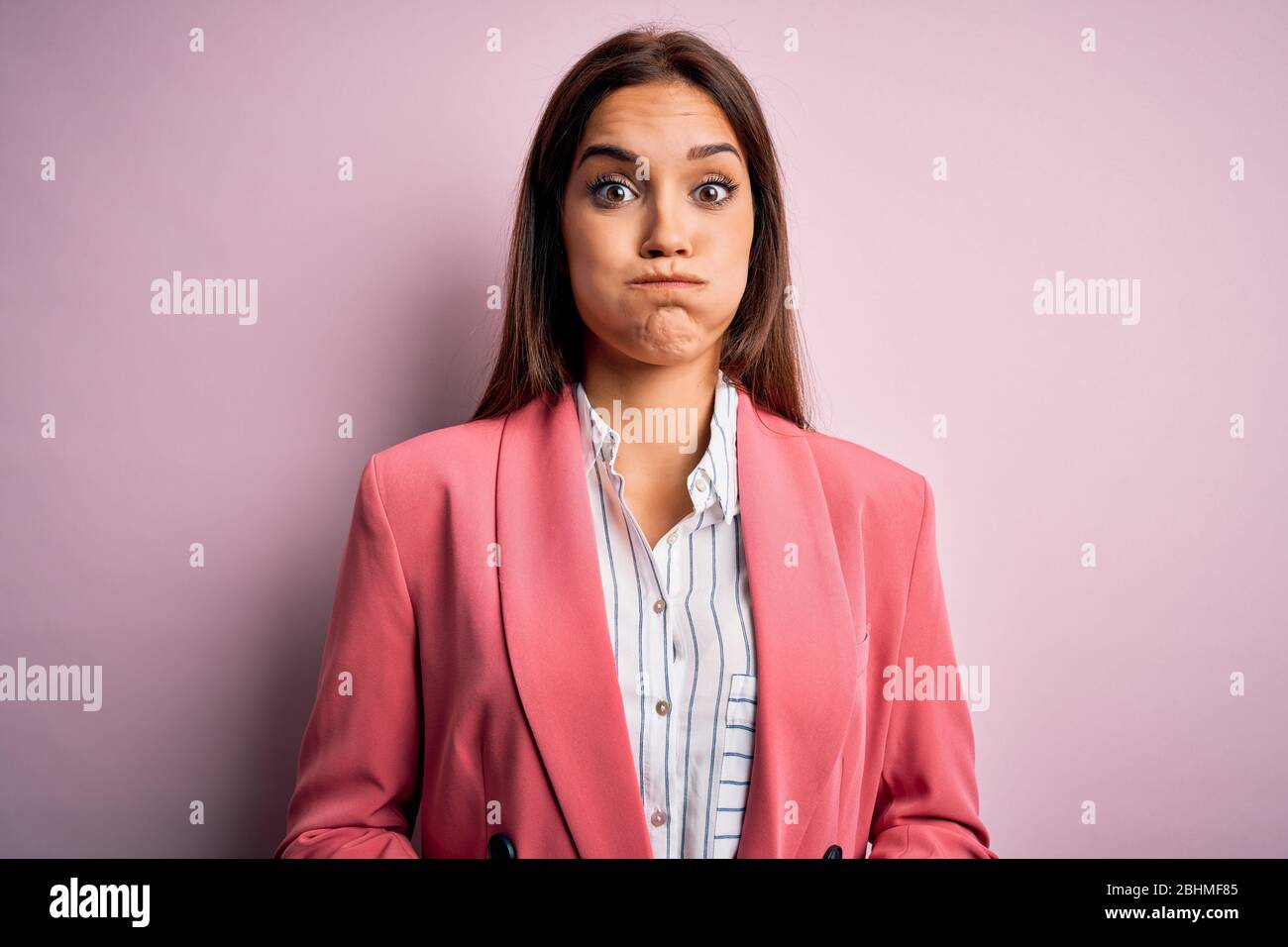 Young beautiful brunette woman wearing jacket standing over isolated ...