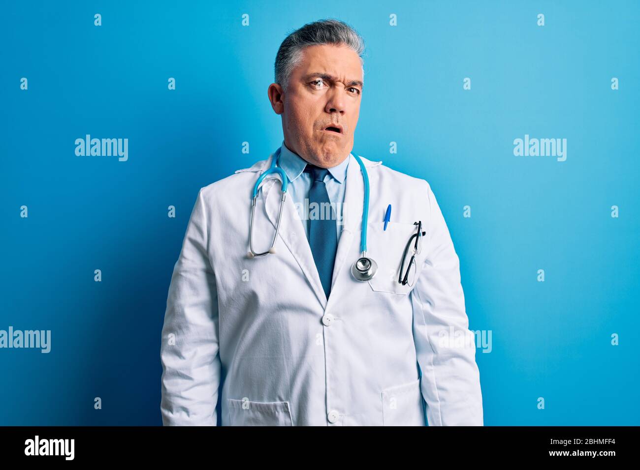 Middle age handsome grey-haired doctor man wearing coat and blue ...