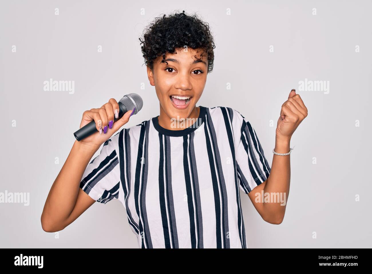 Beautiful african american afro singer woman singing using microphone ...
