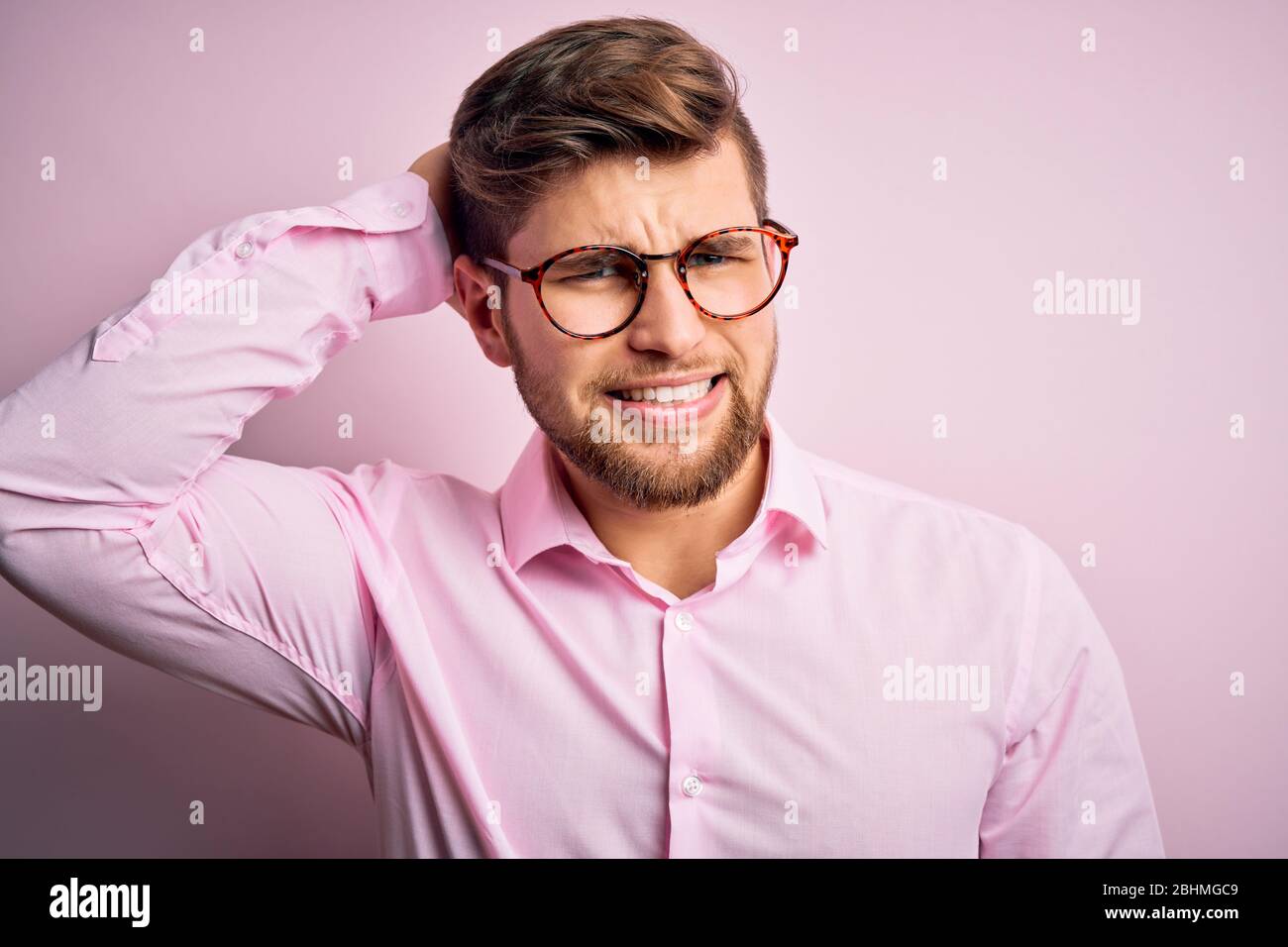 Young handsome blond man with beard and blue eyes wearing pink shirt ...