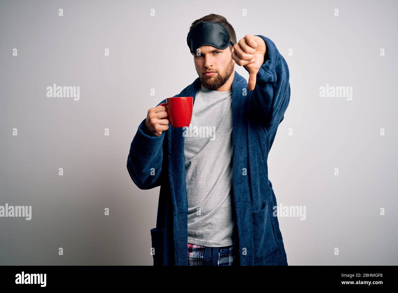 Young blond man with beard and blue eyes wearing pajama drinking cup of ...