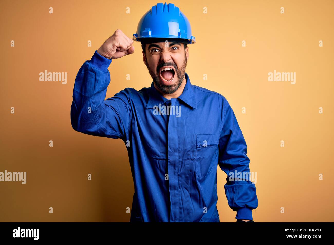 Mechanic man with beard wearing blue uniform and safety helmet over ...
