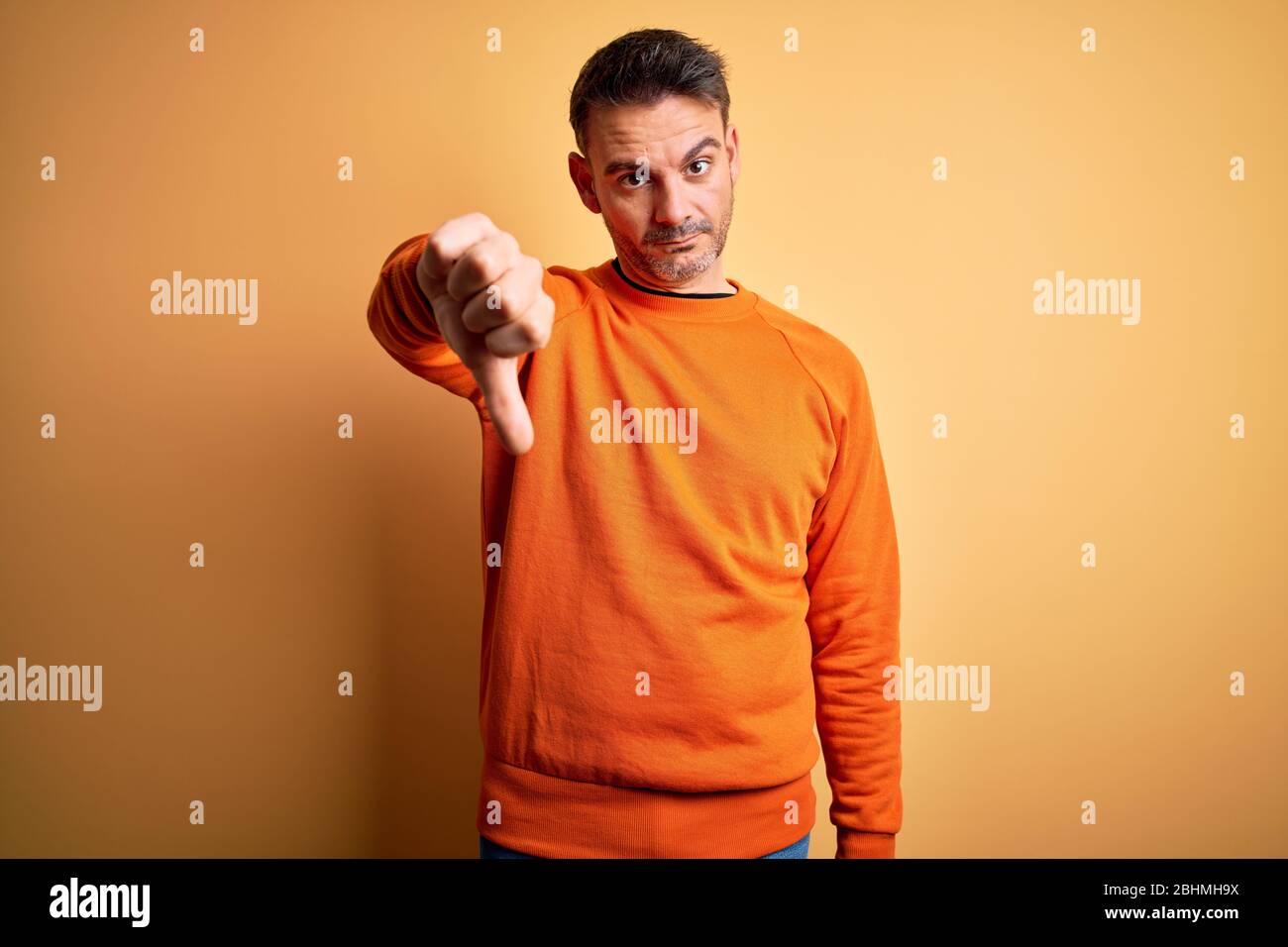 Young handsome man wearing orange casual sweater standing over isolated ...