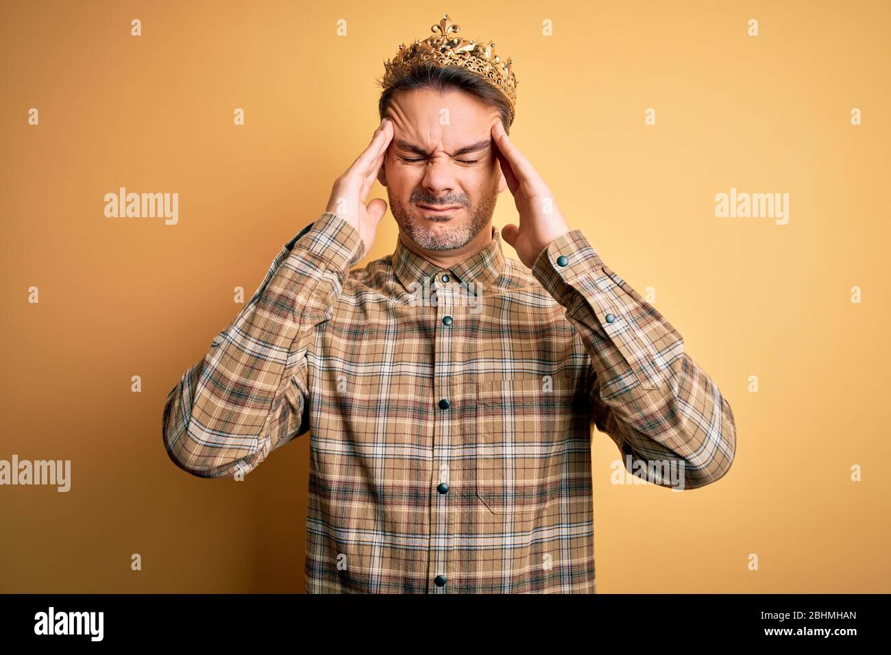 Young handsome man wearing golden crown of king over isolated yellow ...