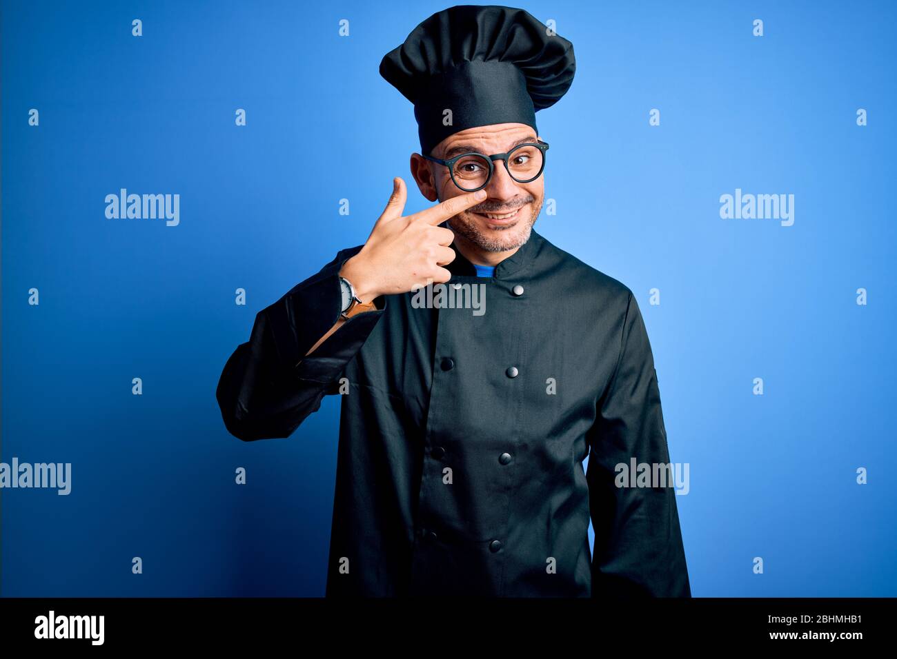 Young handsome chef man wearing cooker uniform and hat over isolated ...