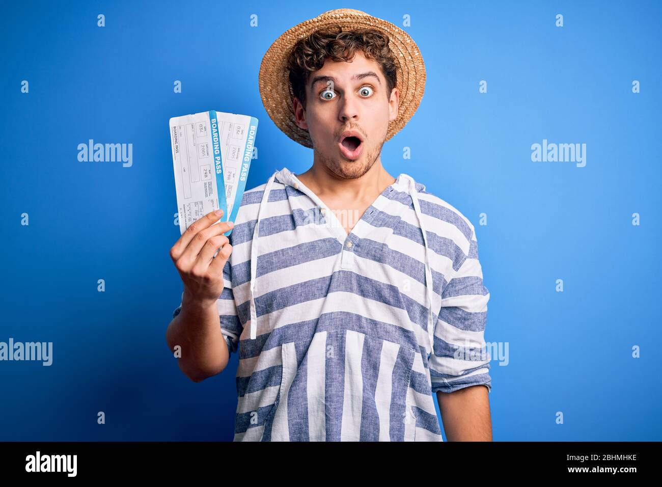 Young blond tourist man with curly hair on vacation wearing summer hat ...