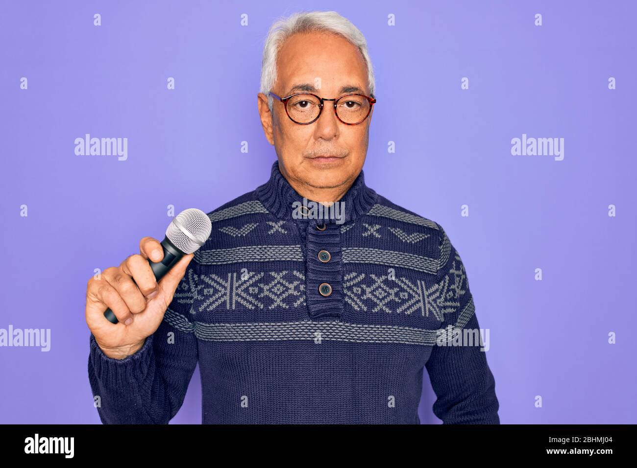 Middle age senior grey-haired singer man singing using music microphone ...