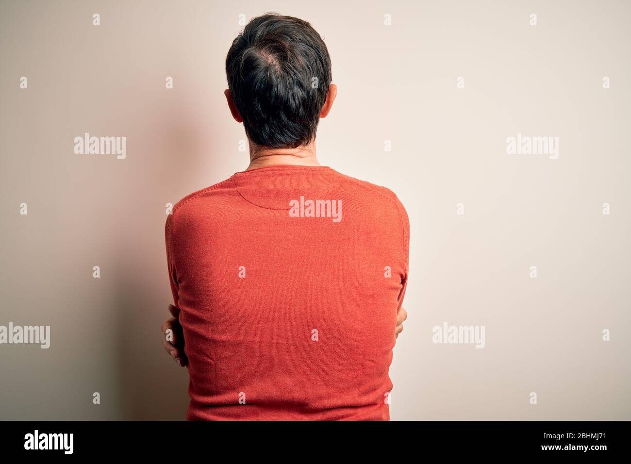 Middle age hoary man wearing casual orange sweater standing over ...