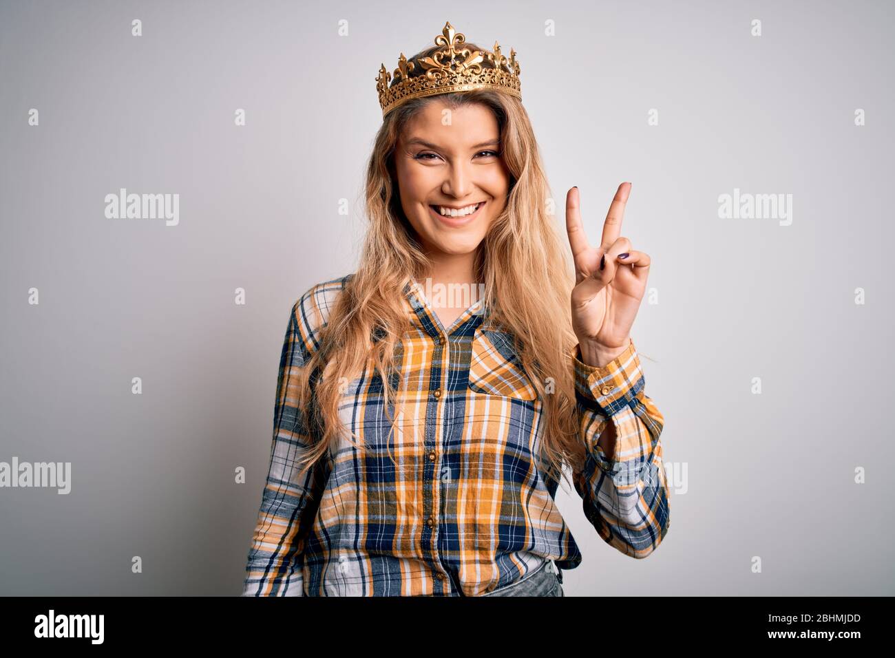 Young beautiful blonde woman wearing golden crown of queen over ...