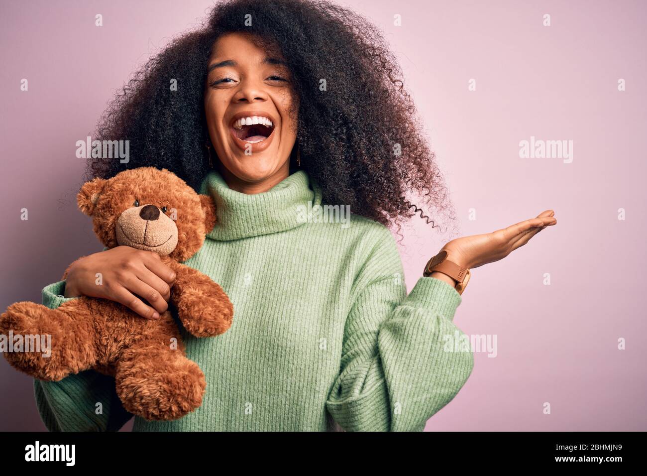 Young african american woman with afro hair hugging teddy bear over ...