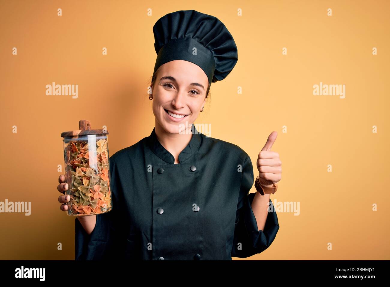 Young beautiful chef woman wearing cooker uniform and hat holding ...