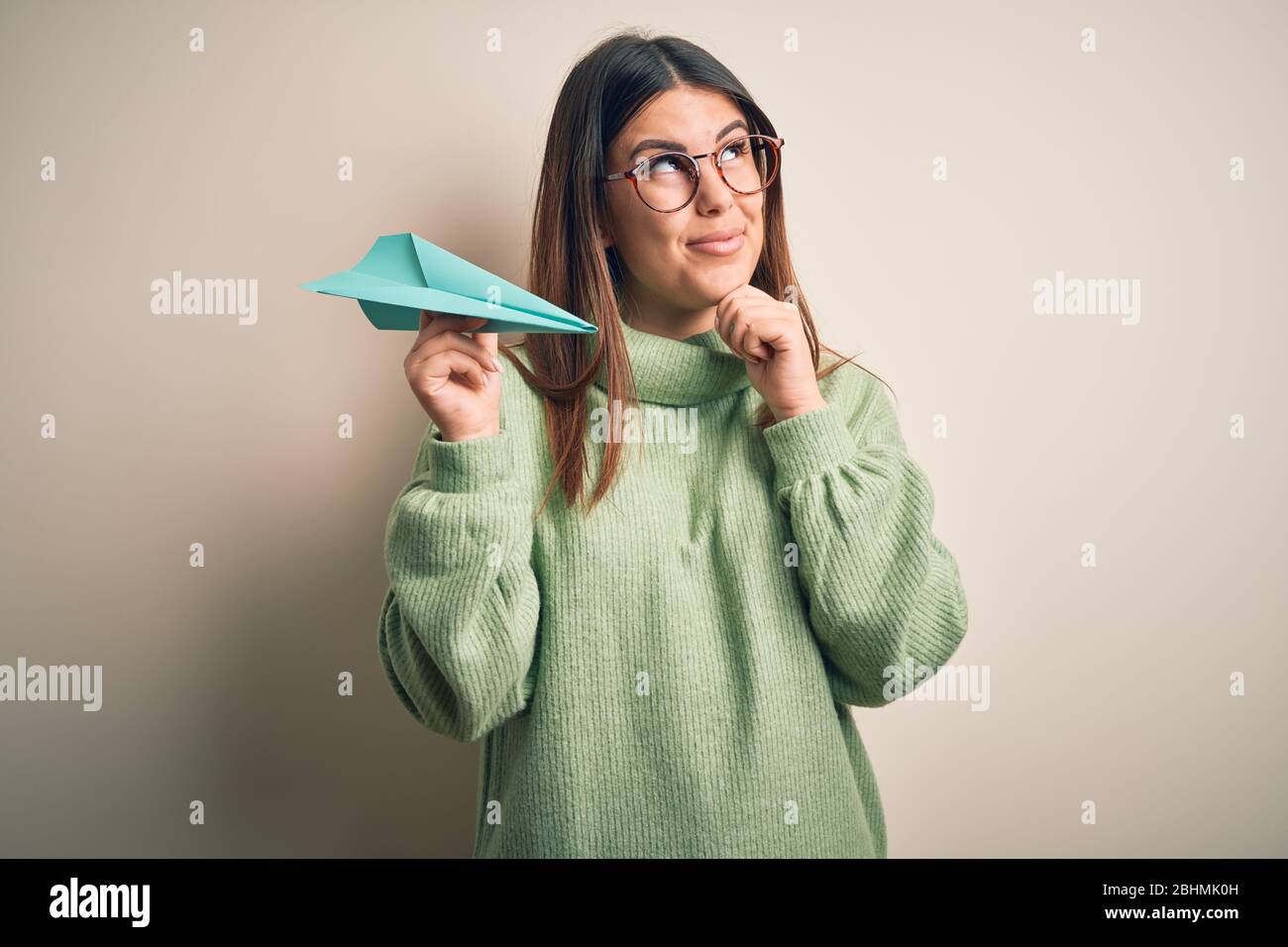 Young beautiful woman holding airplane of paper standing over isolated ...