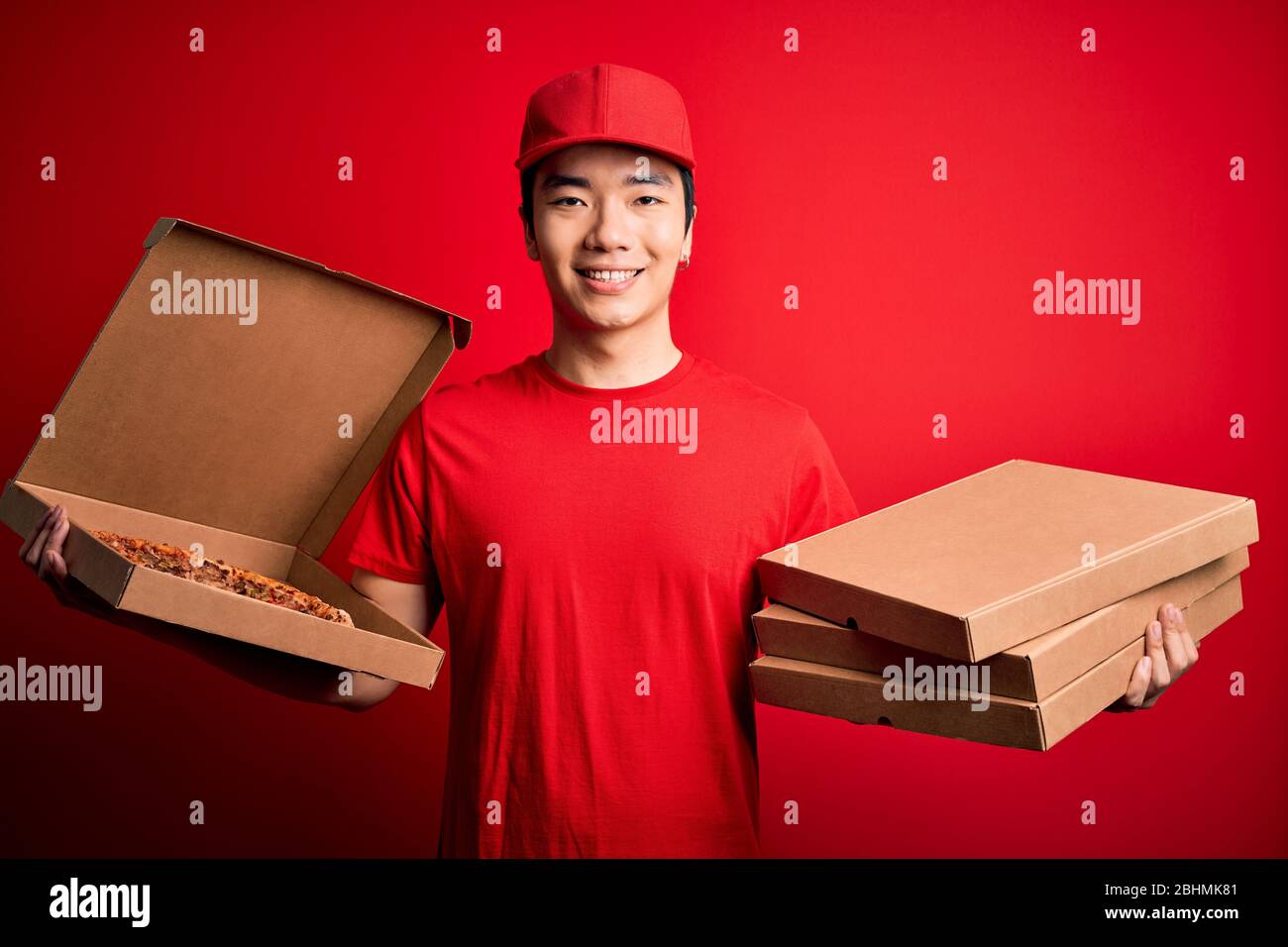 Young handsome chinese delivery man holding deliver boxes with Italian ...
