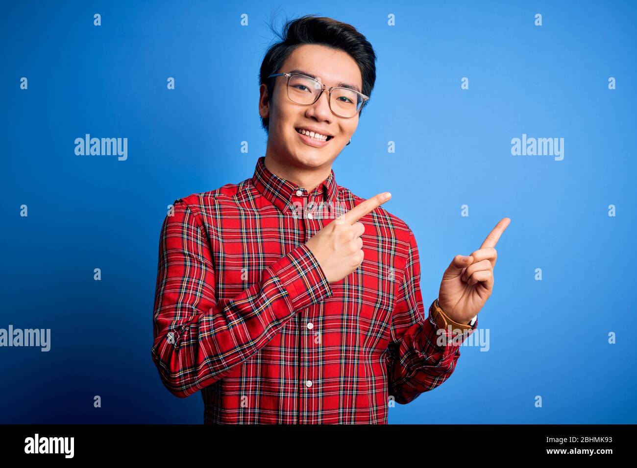 Young Handsome Chinese Man Wearing Casual Shirt And Glasses Over Blue