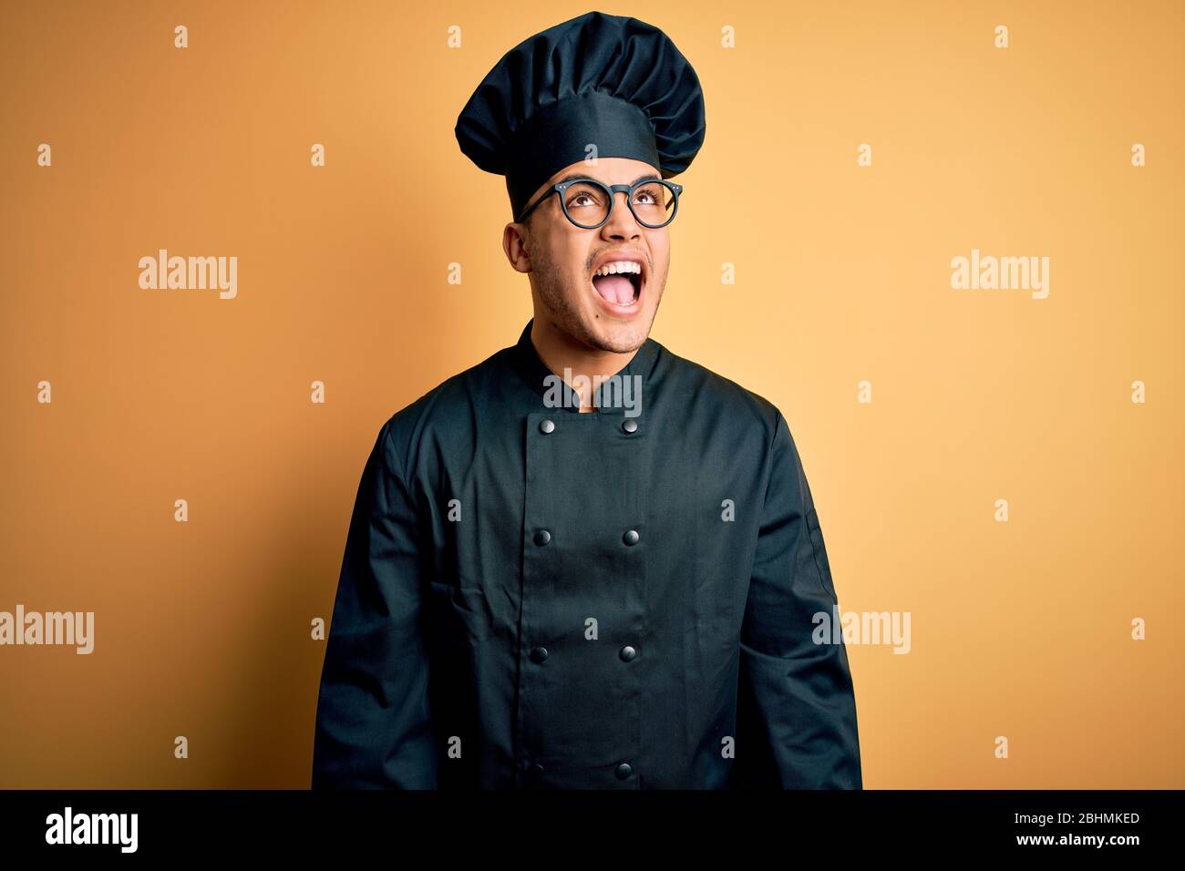 Young brazilian chef man wearing cooker uniform and hat over isolated ...