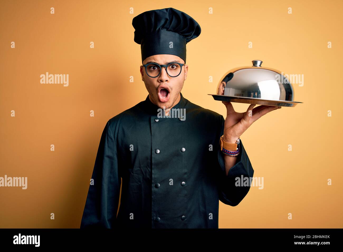 Young brazilian chef man wearing cooker uniform and hat holding tray ...