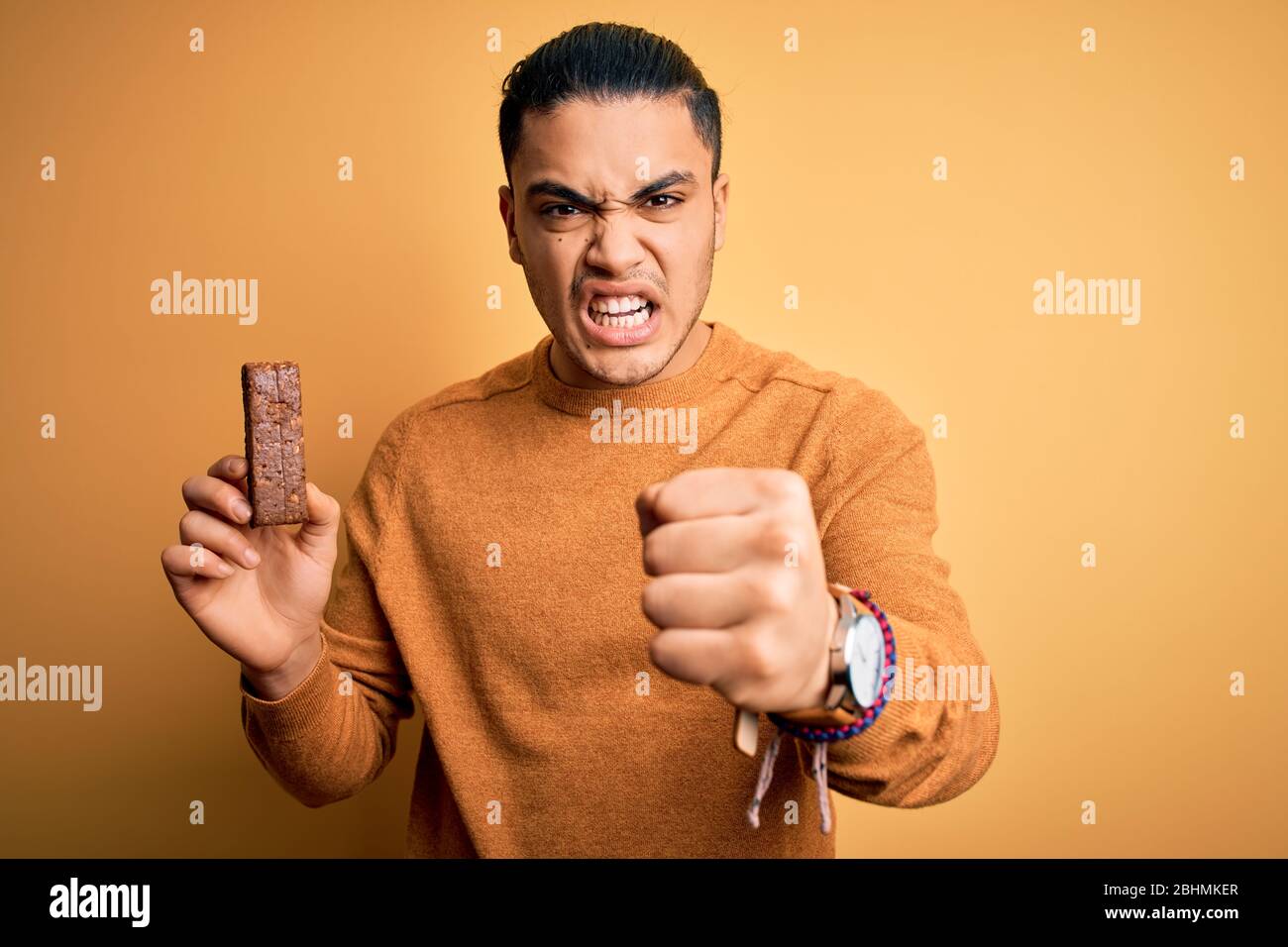 Young brazilian man eating healthy energy bar with protein over ...