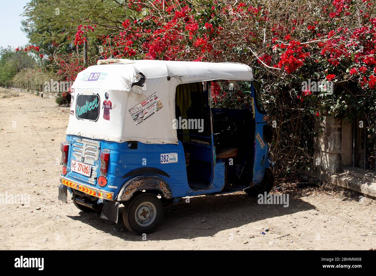 White and Blue Auto Rickshaw or Ethiopian Bajaj parked by a Fence ...