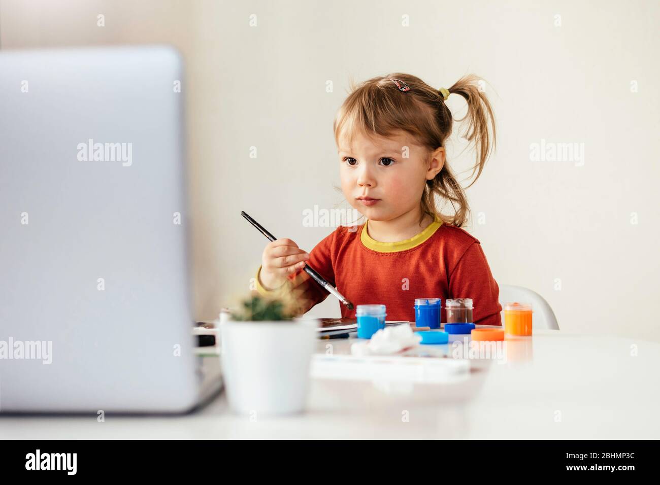 Young cute girl spending a time drawing using online lessons on laptop ...