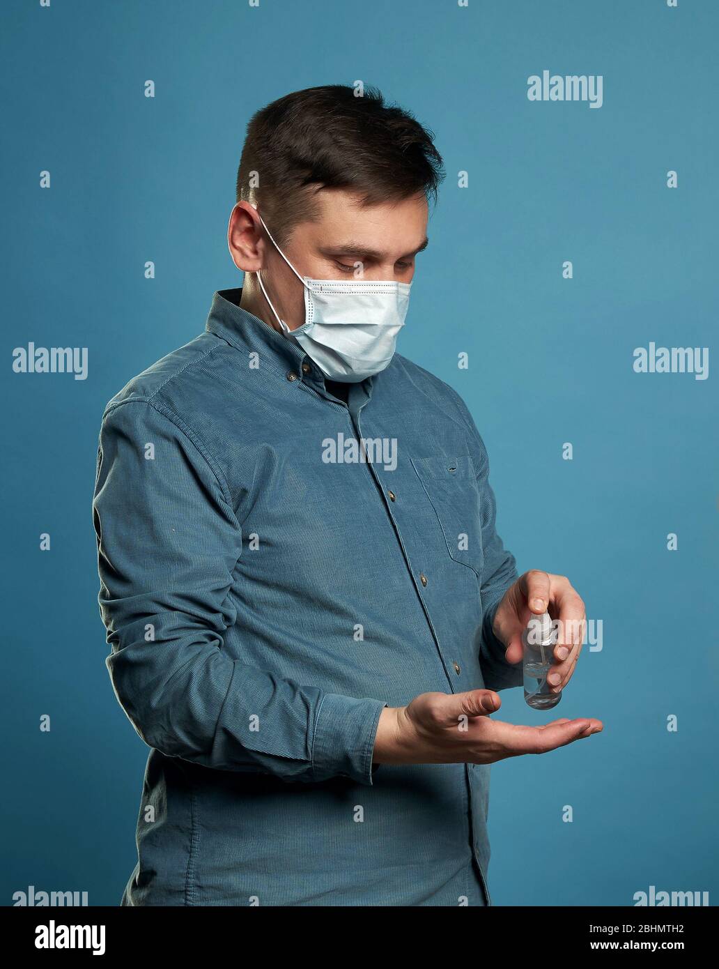 doctor applying antibacterial spray on patient hands on blue background ...