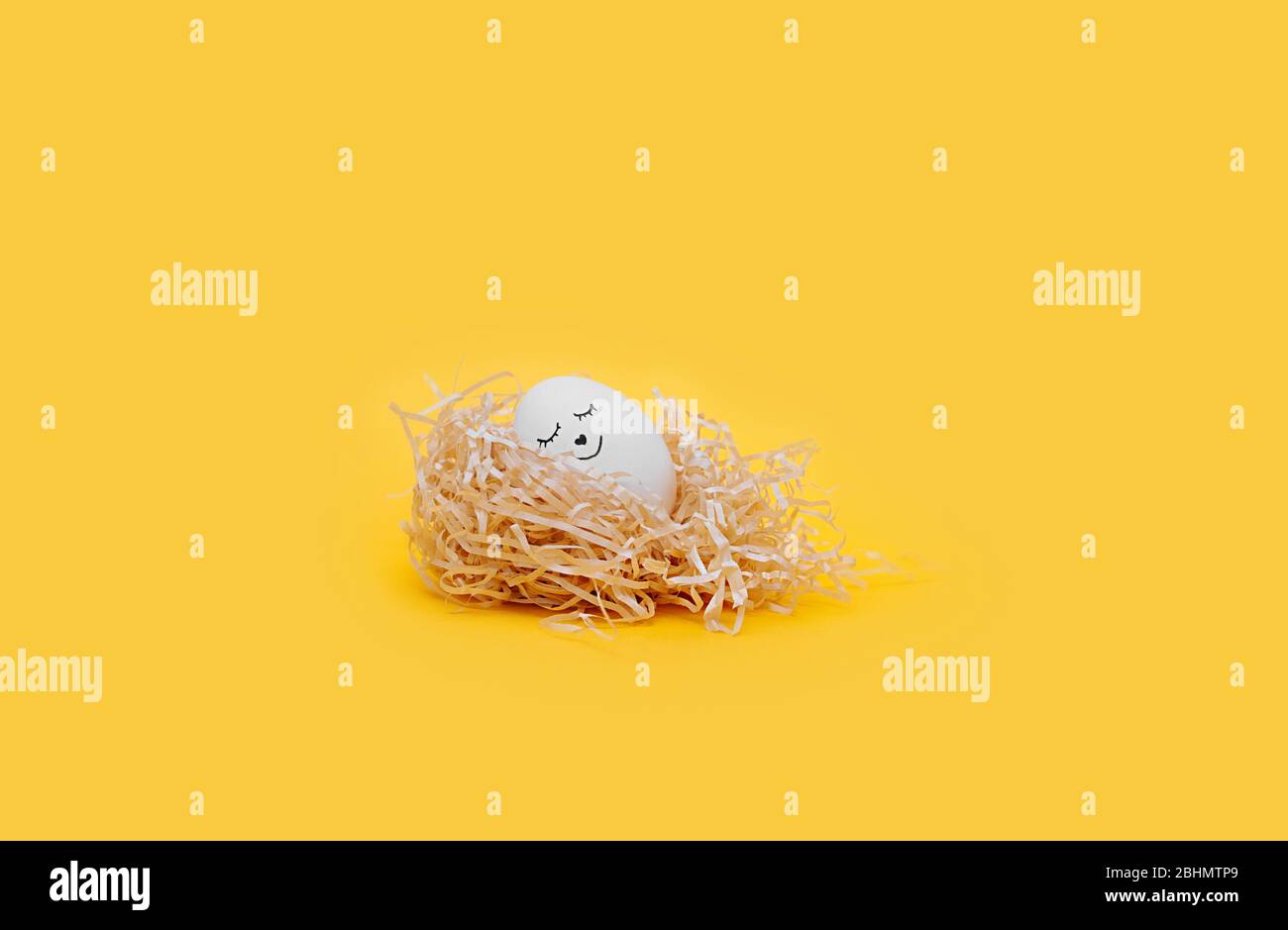 cute white Easter egg with a black marker drawn face sleep in a paper ...