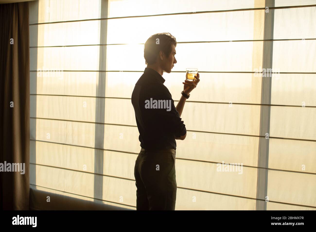 Young Chinese businessman drinking alcohol in front of window Stock ...