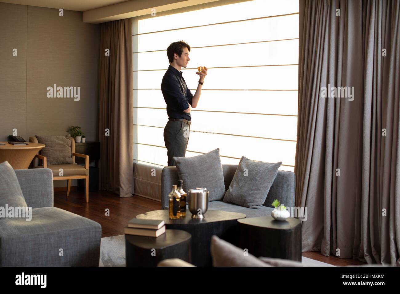 Young Chinese businessman drinking alcohol in front of window Stock ...